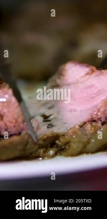 Chef slicing freshly grilled juicy beef steak meat with a knife on a ...