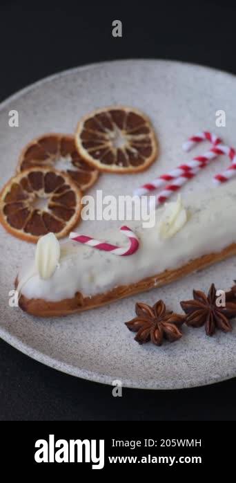 Sweet eclair with chocolate filling covered with white glaze on dark ...