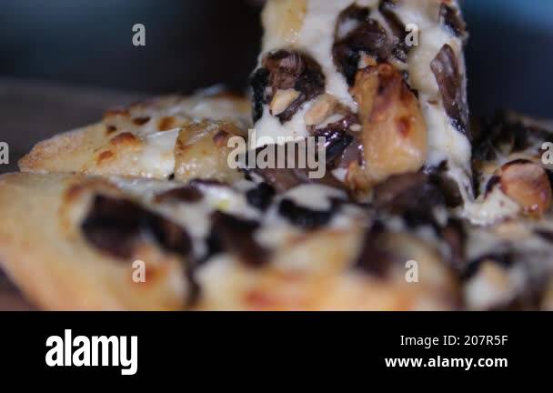 A steady shot shows a cooked mix pizza on a wooden plate while a pizza ...