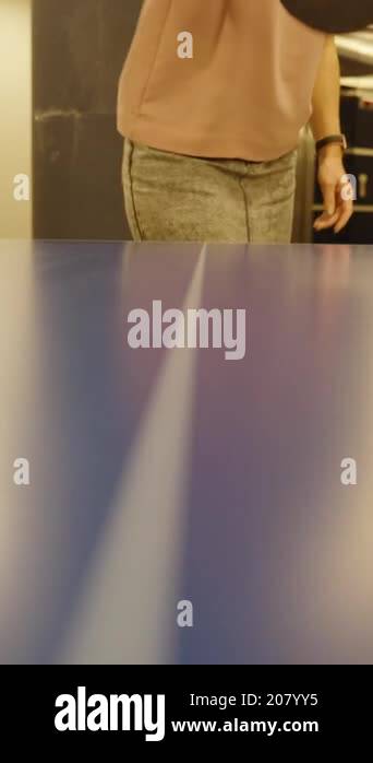 Vertical video. A close-up low-angle shot of a person hitting a ping ...