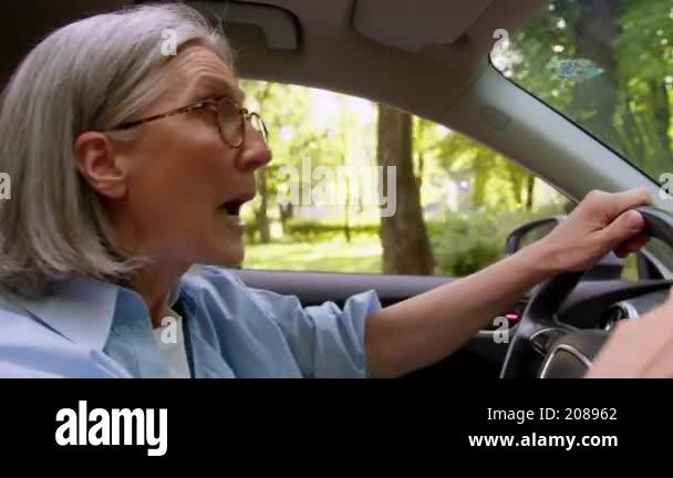 Angry frustrated mad Caucasian mature elderly taxi vehicle driver woman ...