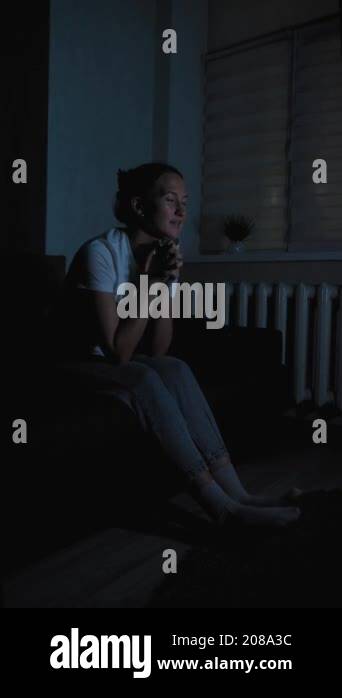 Young woman sitting on couch, expressing excitement and joy while ...