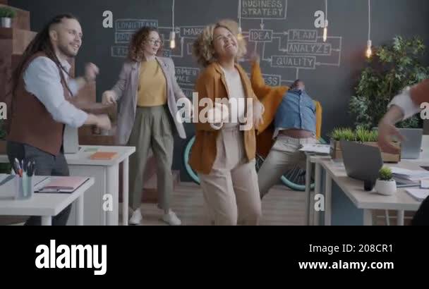 Group of excited businesspeople dancing in creative office enjoying ...