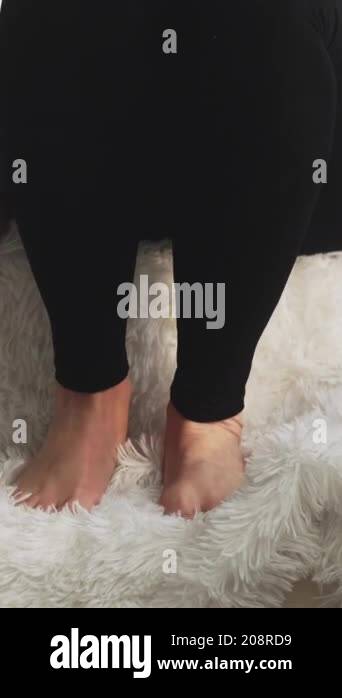 Vertical video. Cold feet. Heating problem. Freezing woman rubbing toes ...