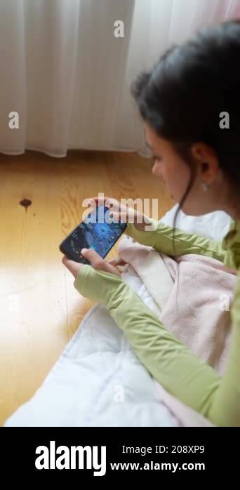 A young individual deeply engaged in their smartphone activities while ...