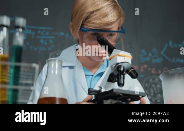 Smart boy using microscope analysis sample at science laboratory in STEM science class or ...