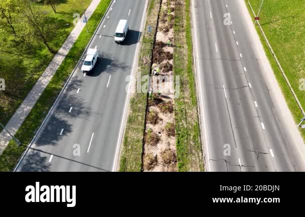 Aerial view of a highway with workers planting trees in the median ...