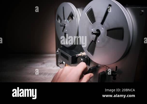 A hand adjusts controls on a vintage reel-to-reel tape recorder in ...