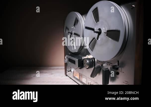 Classic reel-to-reel tape recorder with spinning reels sitting on a ...