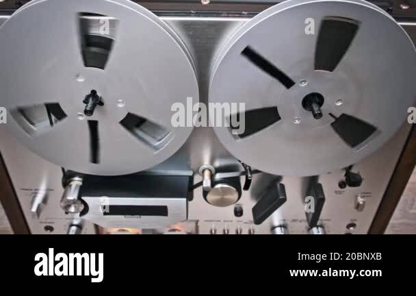 A detailed view of spinning reels on a vintage tape recorder showcases ...