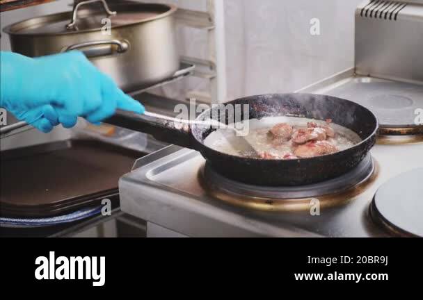 Chef in restaurant kitchen fry chicken liver in hot pan. Professional ...