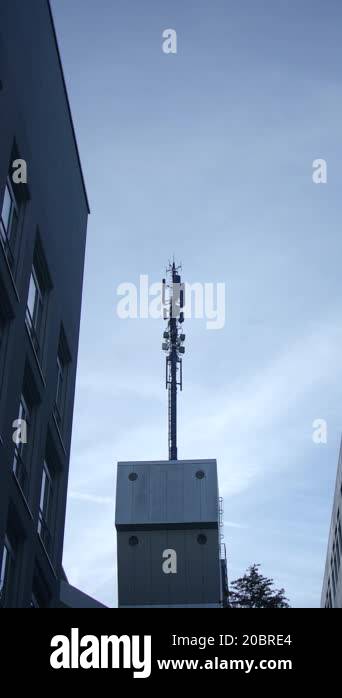A tall telecommunications tower dramatically rises amidst buildings ...