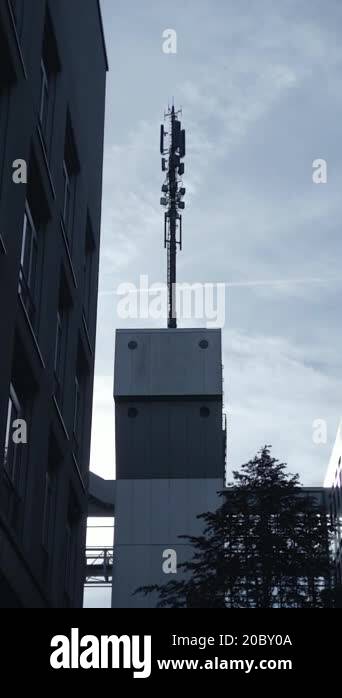 A striking silhouette of a tall telecommunication tower stands out amidst a bustling modern ...
