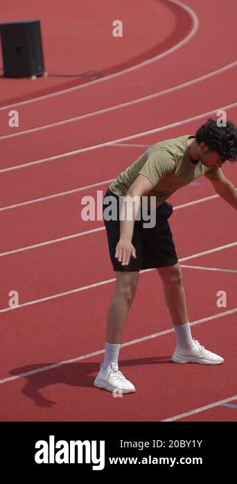 A weary runner taking a moment to catch their breath on the track ...