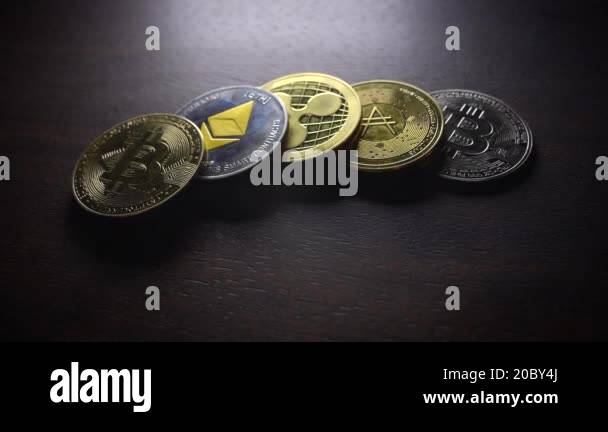A collection of various cryptocurrency coins arranged on a dark surface ...