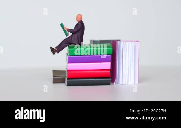 Miniature scene featuring a businessman figurine in a suit sitting on a ...