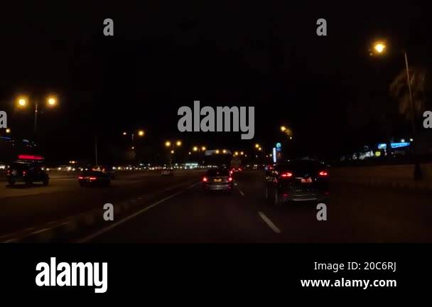 A night time view of a traffic junction, showcasing vehicles waiting as the green light flickers ...