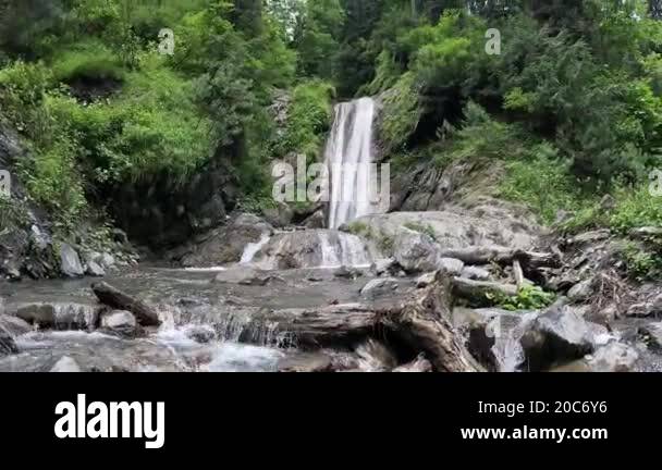 A majestic waterfall cascades gracefully down rocky cliffs, surrounded ...