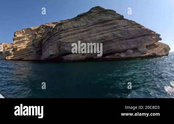 A magnificent rock formation juts out of the tranquil waters waves ...