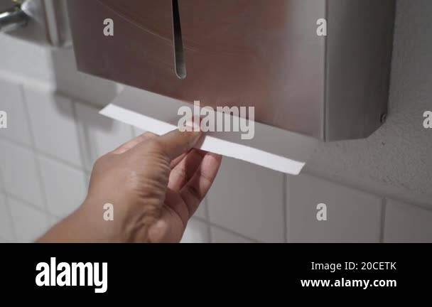 Hand taking paper towel from a dispenser in a clean public restroom ...
