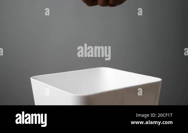 A hand dropping bread into a white container, highlighting food wastes ...