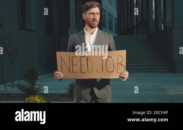 Upset young businessman holding poster cardboard with Need Job jobless ...