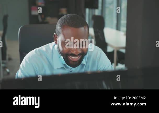 Handsome smiling African American man removes mask uses computer for ...