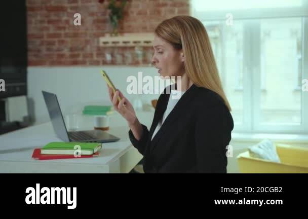 Portrait angry businesswoman speaking on cellphone at home kitchen ...