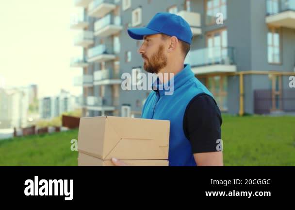Handsome young happy smiling delivery man holding cardboard box stand ...