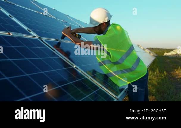 Slow motion man worker fixing solar panel to a metal basis with a drill ...