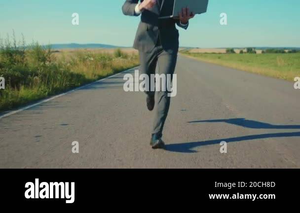 Attractive serious businessman walking use laptop alone country road ...