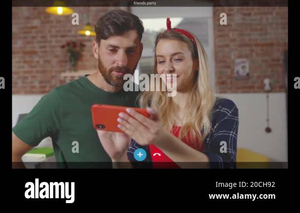 Close up young couple during a video call at the party with friends ...