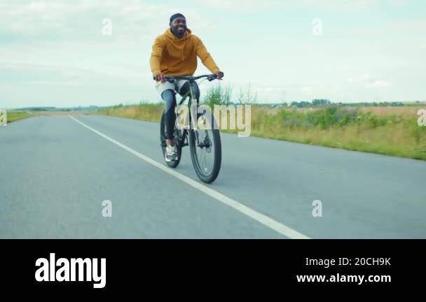 Young smiling african american man in cycling on road in the ...