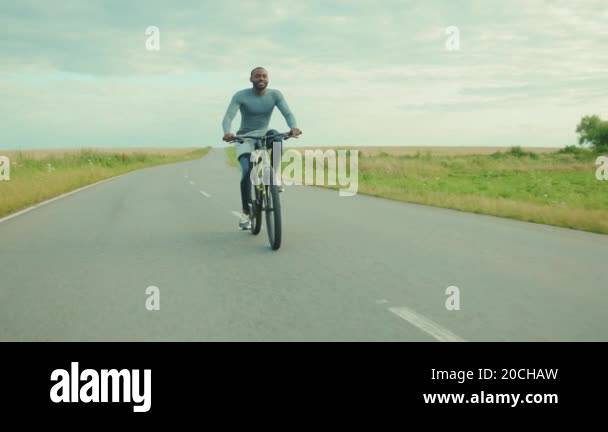 Close up smiling african american man in cycling on road in the ...