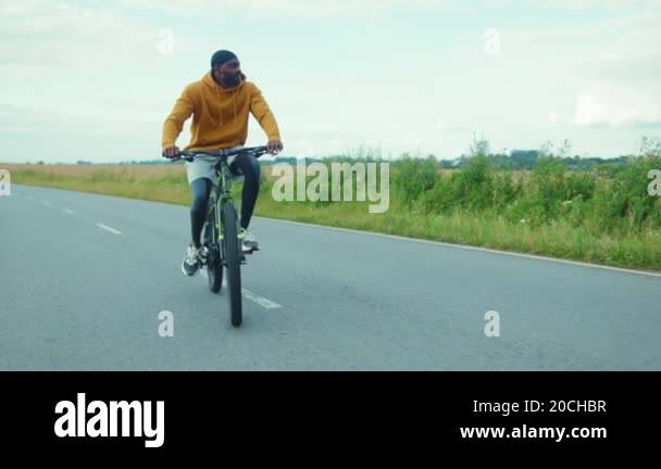 Happy african american man in cycling on road in the countryside ...