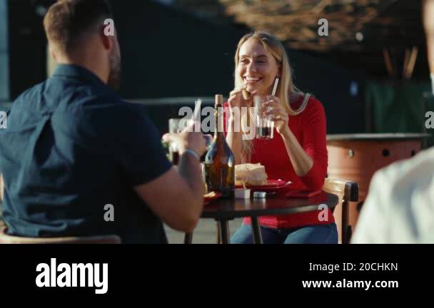 Young relaxing man and woman drinking cocktail cheers in street cafe ...