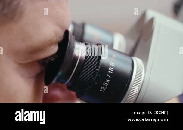 Close up face man dentist looking through dental microscope equipment ...