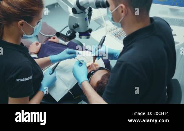 NEW YORK - April 5, 2020: Shot back dentist man with assistant and man as client in professional ...