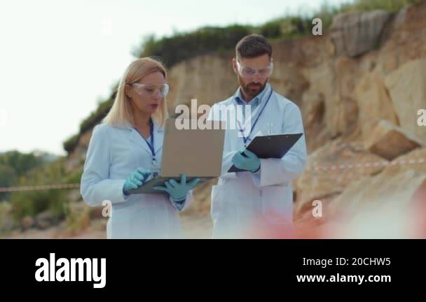 Worker ecology experts use laptop in protection wear working on land relief earth pollution ...