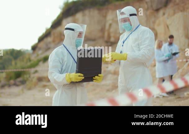 Outdoors ecology experts in protection wear working takes soil samples ...