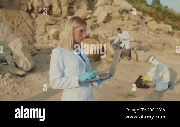 Woman ecology experts in protection wear working on landfill use laptop background people take ...