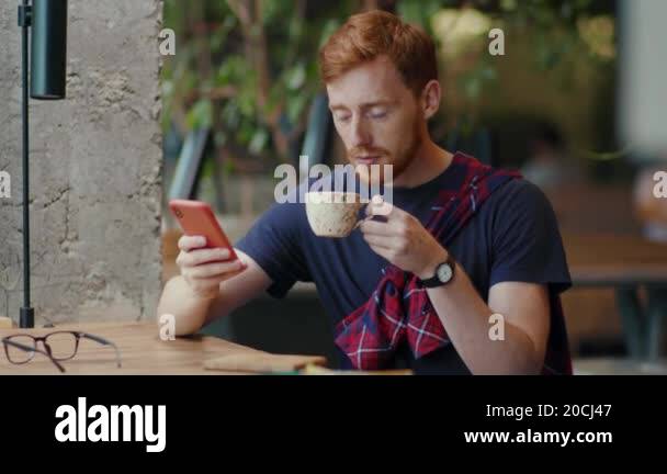 Handsome urban ginger guy using smartphone social networking app ...