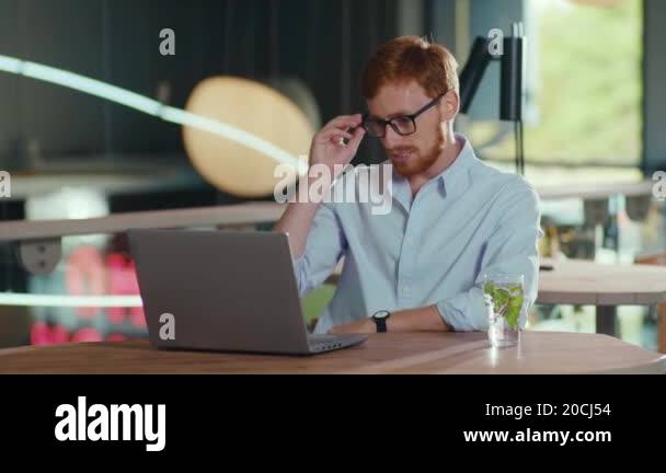 Ginger businessman with eyeglasses speaking at online interview webcam ...
