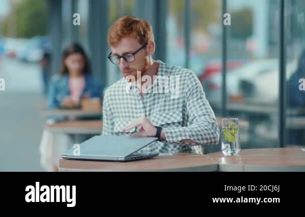 Red-haired attractive ginger young employee sitting in the cafe ...