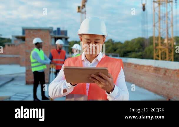 Portrait smiling asian builder standing with tablet computer look at ...