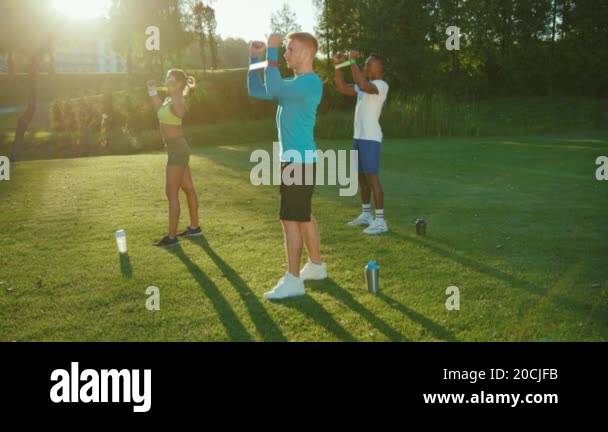 Three active well built athletes training in the meadow on early ...