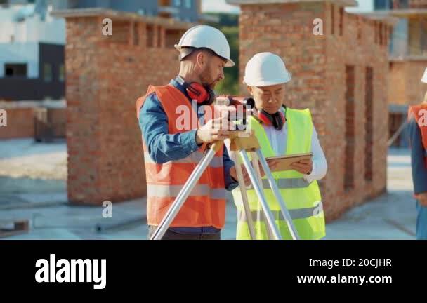 Young serious man engineer surveyor takes measures with theodolite ...