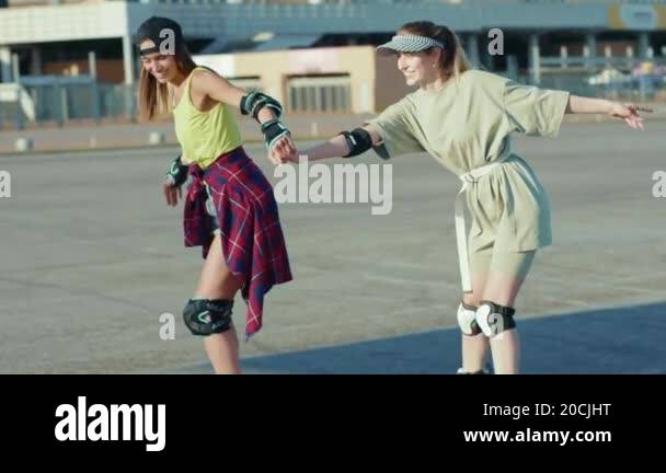 Close up two young pretty girls rolling skating outdoors having fun ...