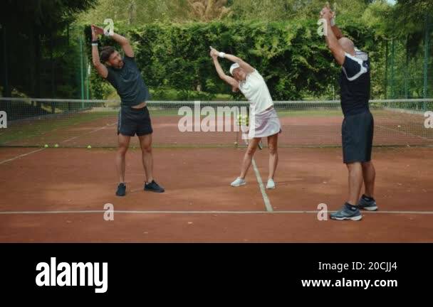 Slow motion players warm up before a game of tennis with trainer ...