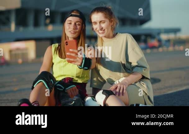 Slow motion young women sitting on ground with roller skates speaking ...